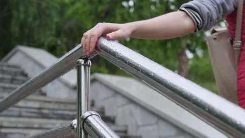 Woman holds hand on wet metal railing, w... | Stock Video | Pond5