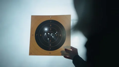 Woman Inspecting Bullet Holes in Paper S... | Stock Video | Pond5