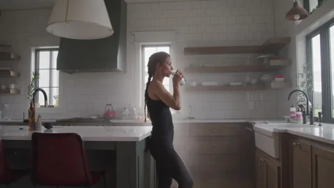 Woman Leans Against Kitchen Counter Drin... | Stock Video | Pond5