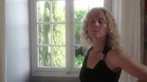 Woman Looks Out Window Turns to Camera | Stock Video | Pond5