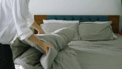 Woman makes the bed, fluffing soft pillo... | Stock Video | Pond5