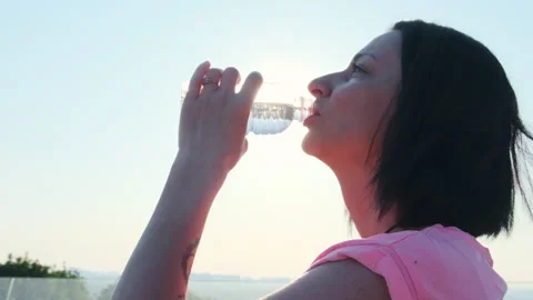 Woman makes sip of water from transparen... | Stock Video | Pond5