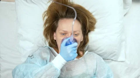 a woman putting on an oxygen mask by her... | Stock Video | Pond5