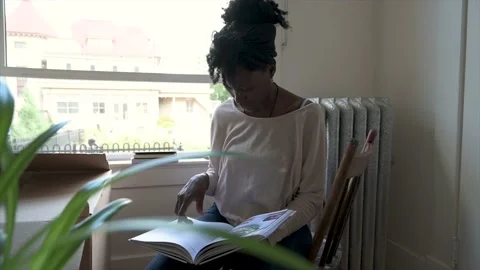 Woman reading book at window, moving int... | Stock Video | Pond5