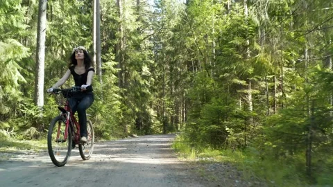 Woman riding bike alone in the forest | Stock Video | Pond5