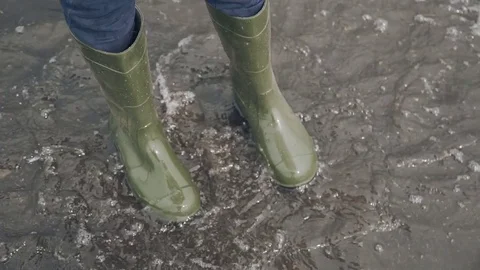 A woman in rubber boots jumping over a p... | Stock Video | Pond5