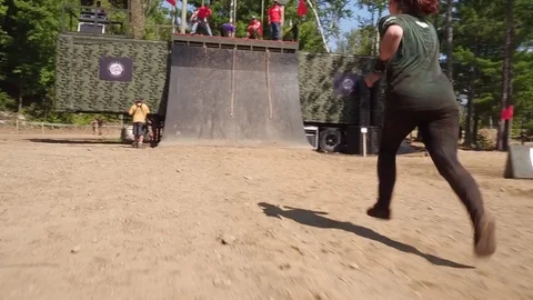 Woman running at a ramp in obstacle race... | Stock Video | Pond5