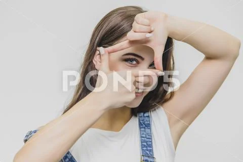 Woman showing frame finger sign. Young woman framing herself with hands ...