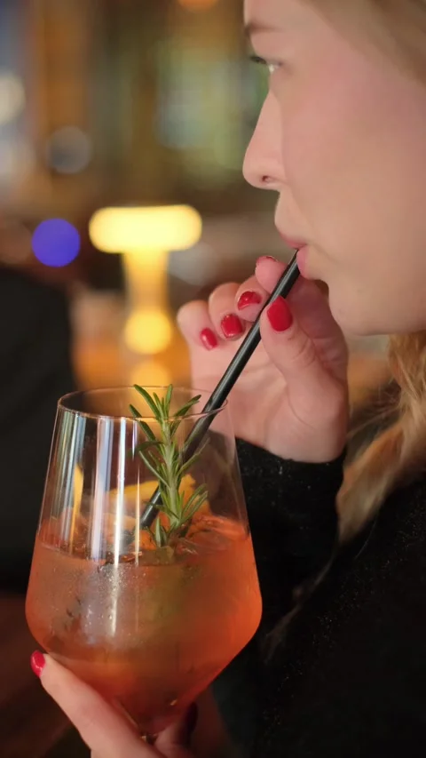 A woman is sipping a cocktail with a str... | Stock Video | Pond5
