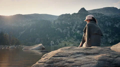Woman sit on rock inferno mountain lake ... | Stock Video | Pond5