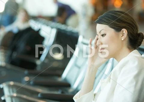 Photograph: Woman sitting in airport lounge, holding head #42242457