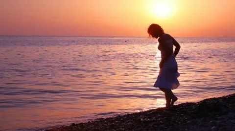 woman sloshing water in sea, sunset sky ... | Stock Video | Pond5