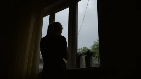 Woman standing at the window in the room... | Stock Video | Pond5