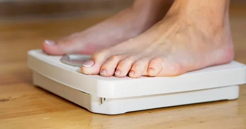A woman stands on white scale on the flo... | Stock Video | Pond5