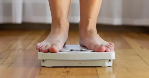 A woman stands on white scale on the flo... | Stock Video | Pond5