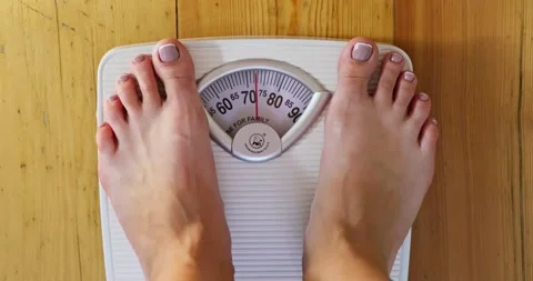 A woman stands on white scale on the flo... | Stock Video | Pond5
