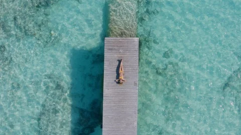 Woman sunbathing on wooden jetty, drone ... | Stock Video | Pond5