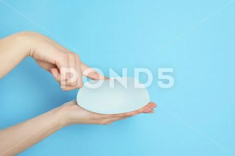 Woman touching silicone implant for breast augmentation on color ...