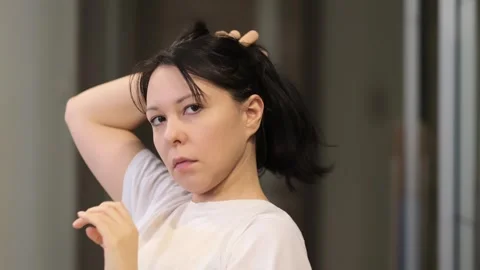 Woman tying her hair back in a casual se... | Stock Video | Pond5
