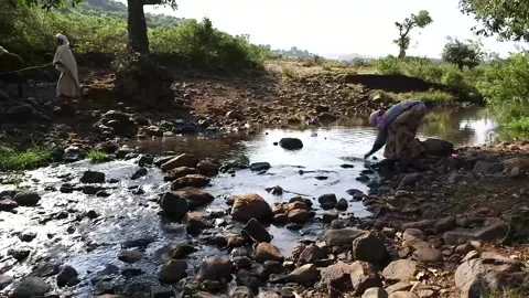 Woman washing clothes by a river stream ... | Stock Video | Pond5