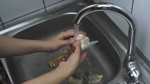 Woman washing garlic under flowing water | Stock Video | Pond5