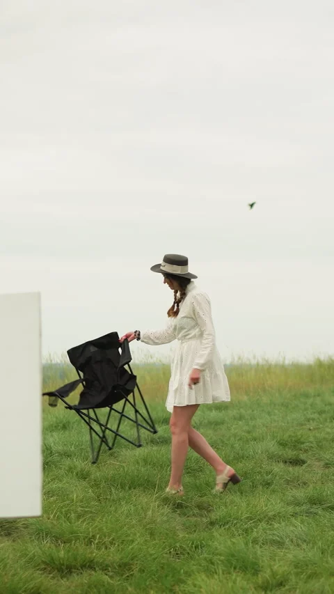 Woman in White Dress Carrying Chair Towa... | Stock Video | Pond5