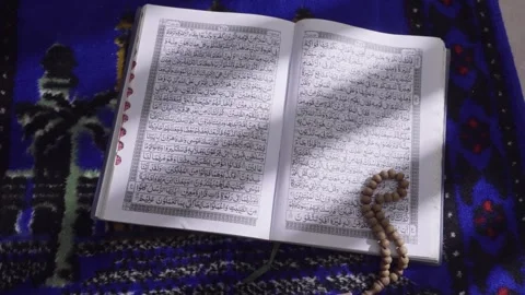 Wooden prayer beads lay across the pages... | Stock Video | Pond5