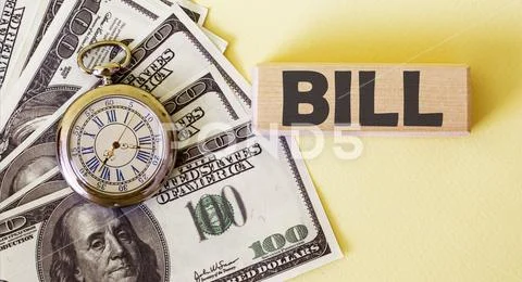 The word Bill is written on a wooden block, a stack of 100 dollars and ...