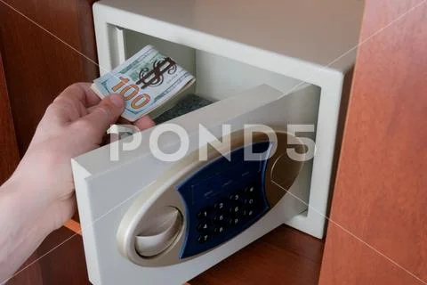 Work with money. A man puts a bundle of dollars in a Bank safe. Income ...