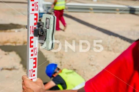 Photograph: Worker is holding leveling rod to measuring level on ...