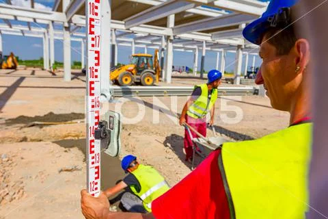 Worker is holding leveling rod to measuring level on construction site ...