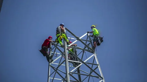 Workers stand on metal powerline structu... | Stock Video | Pond5