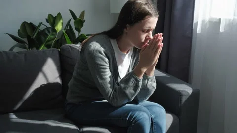 Worried woman sitting on couch praying g... | Stock Video | Pond5