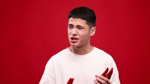 Young asian man eating red hot chilli pe... | Stock Video | Pond5
