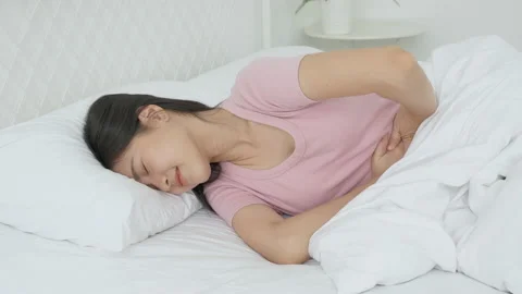 Young asian woman lying on bed pain stom... | Stock Video | Pond5