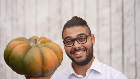 A young bearded guy holds a pumpkin and ... | Stock Video | Pond5