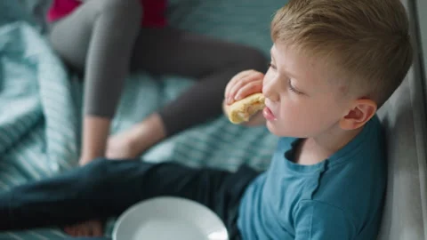 Young Boy Eating Snack on Bed with Parti... | Stock Video | Pond5