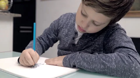 Young boy focused colouring his drawing | Stock Video | Pond5