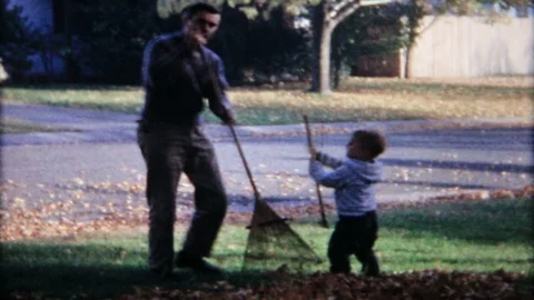 young boy helps dad rake leaves in the f... | Stock Video | Pond5