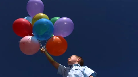 Young boy lets balloons go into sky, slo... | Stock Video | Pond5