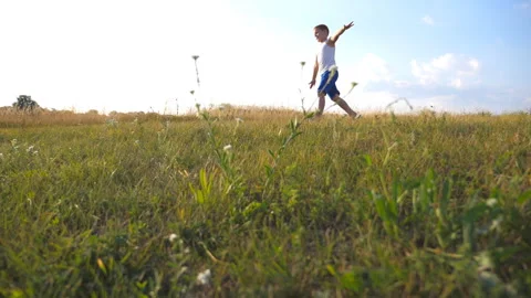 Young boy with raised hands running on g... | Stock Video | Pond5