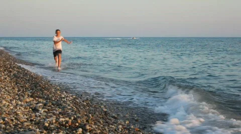 young boy running on pebble beach to cam... | Stock Video | Pond5