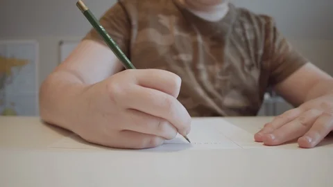 a young boy writing on paper with a penc... | Stock Video | Pond5