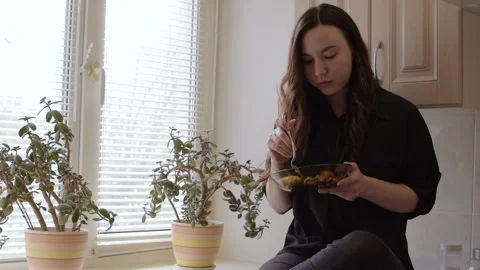 A young brunette girl sits on a kitchen ... | Stock Video | Pond5