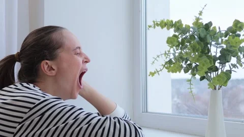 Young Caucasian woman yawning while sitt... | Stock Video | Pond5