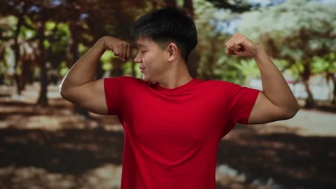 Young chinese man flexing muscles outdoo... | Stock Video | Pond5