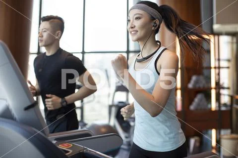 Young Chinese people running on treadmill at gym ~ Hi Res #253456983
