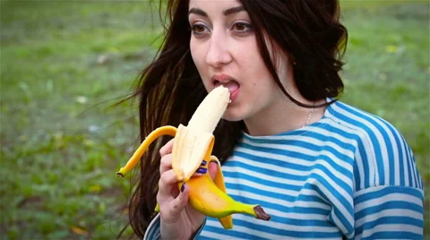 Young girl biting a banana in the Park | Stock Video | Pond5
