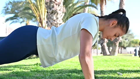 Young girl doing push-ups in the park, s... | Stock Video | Pond5