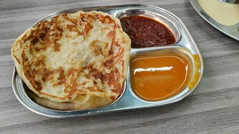 A young girl enjoys roti canai, a popula... | Stock Video | Pond5